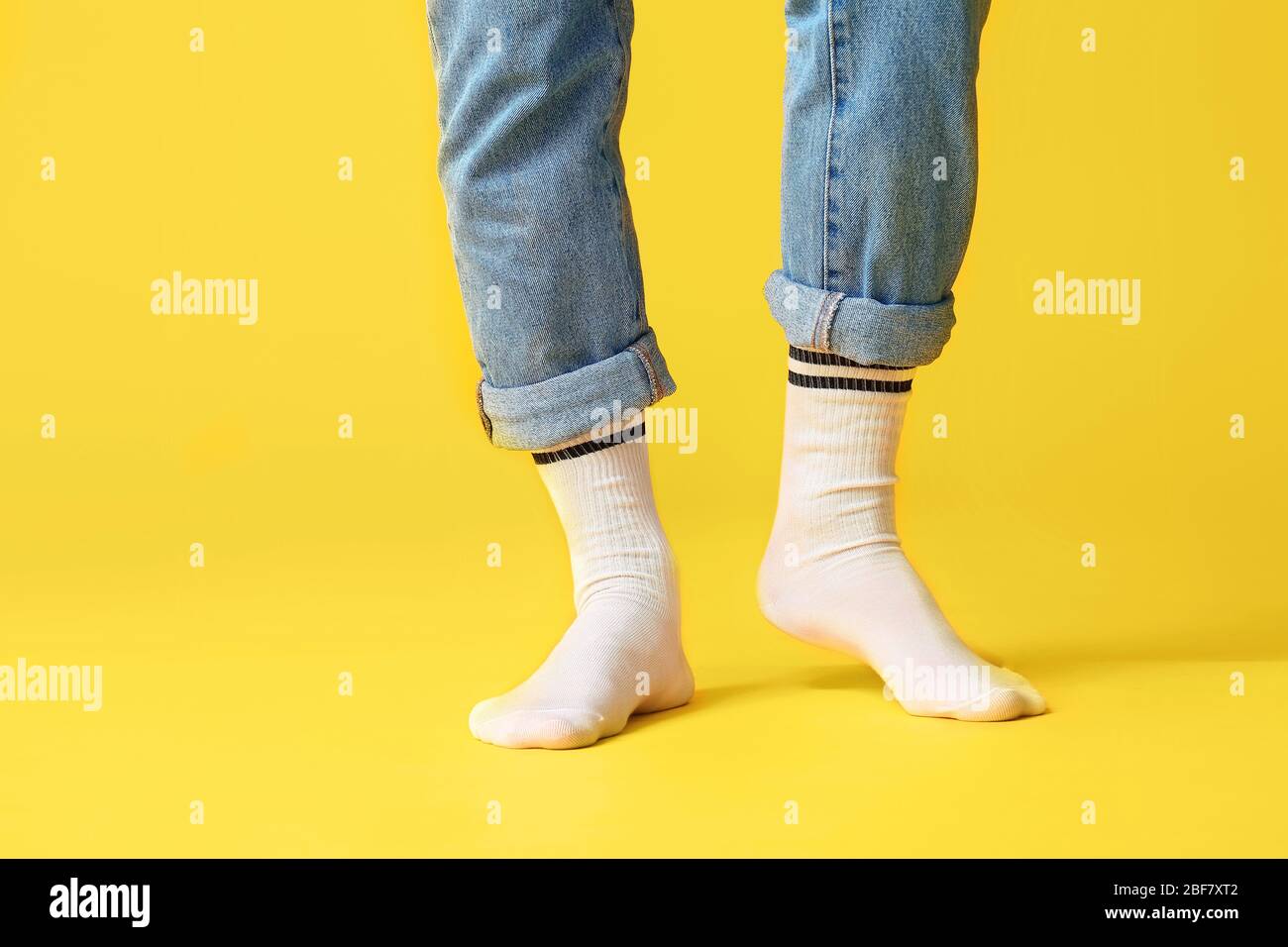 Male legs in socks and jeans on color background Stock Photo - Alamy
