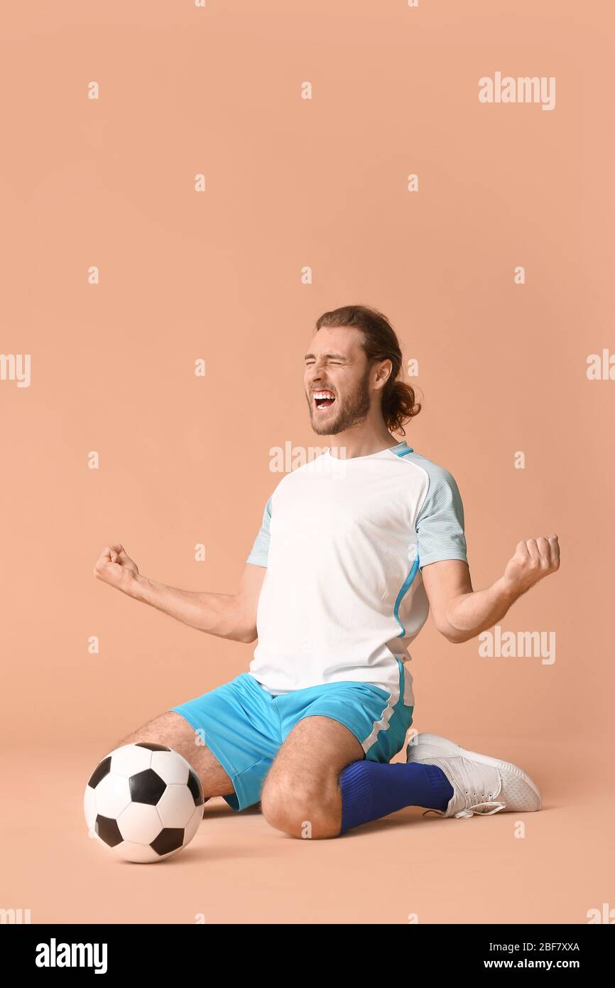 Happy football player on color background Stock Photo - Alamy