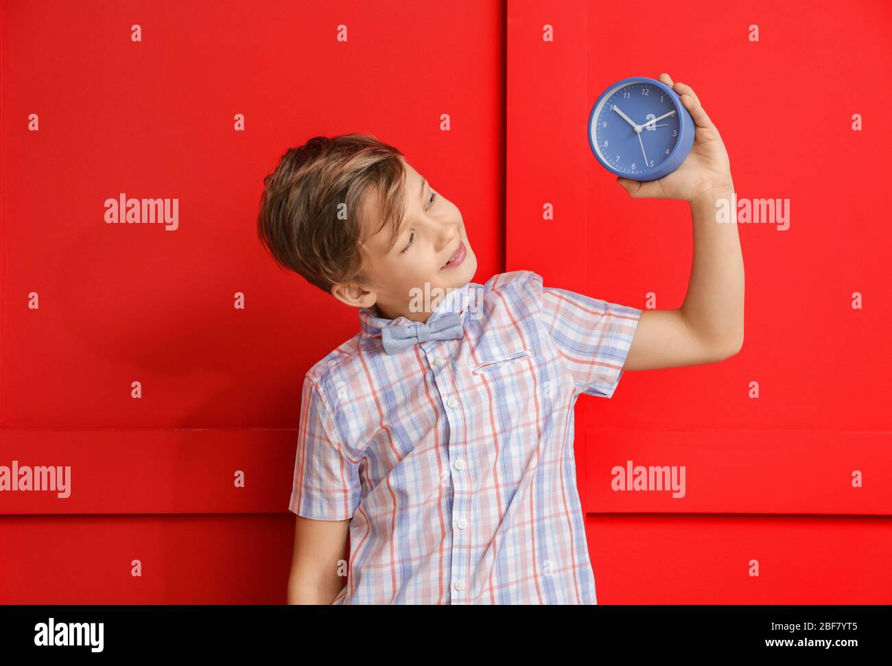 Little boy with alarm clock on color background Stock Photo - Alamy