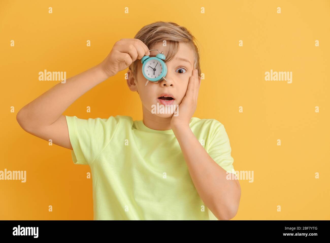 Shocked little boy with alarm clock on color background Stock Photo - Alamy