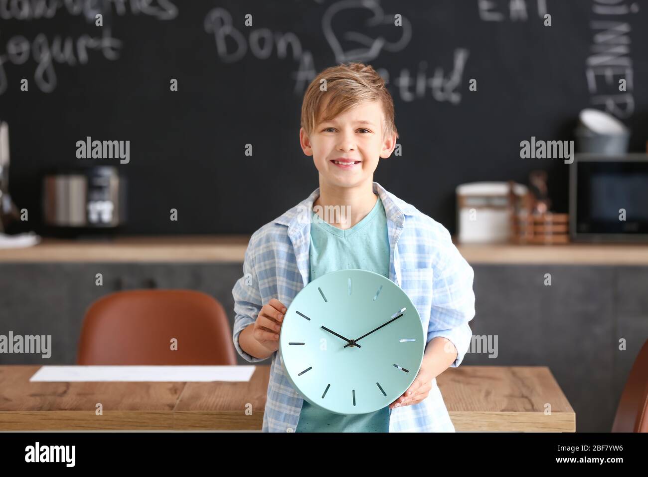Little boy with clock in kitchen Stock Photo - Alamy