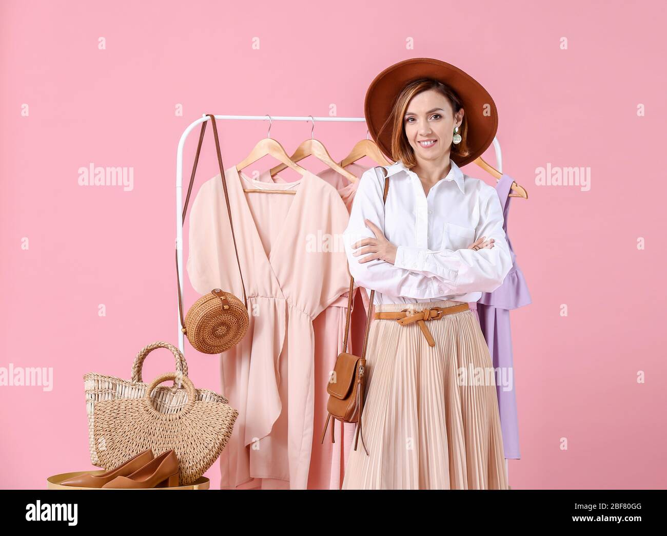 Female stylist near rack with modern clothes on color background Stock ...