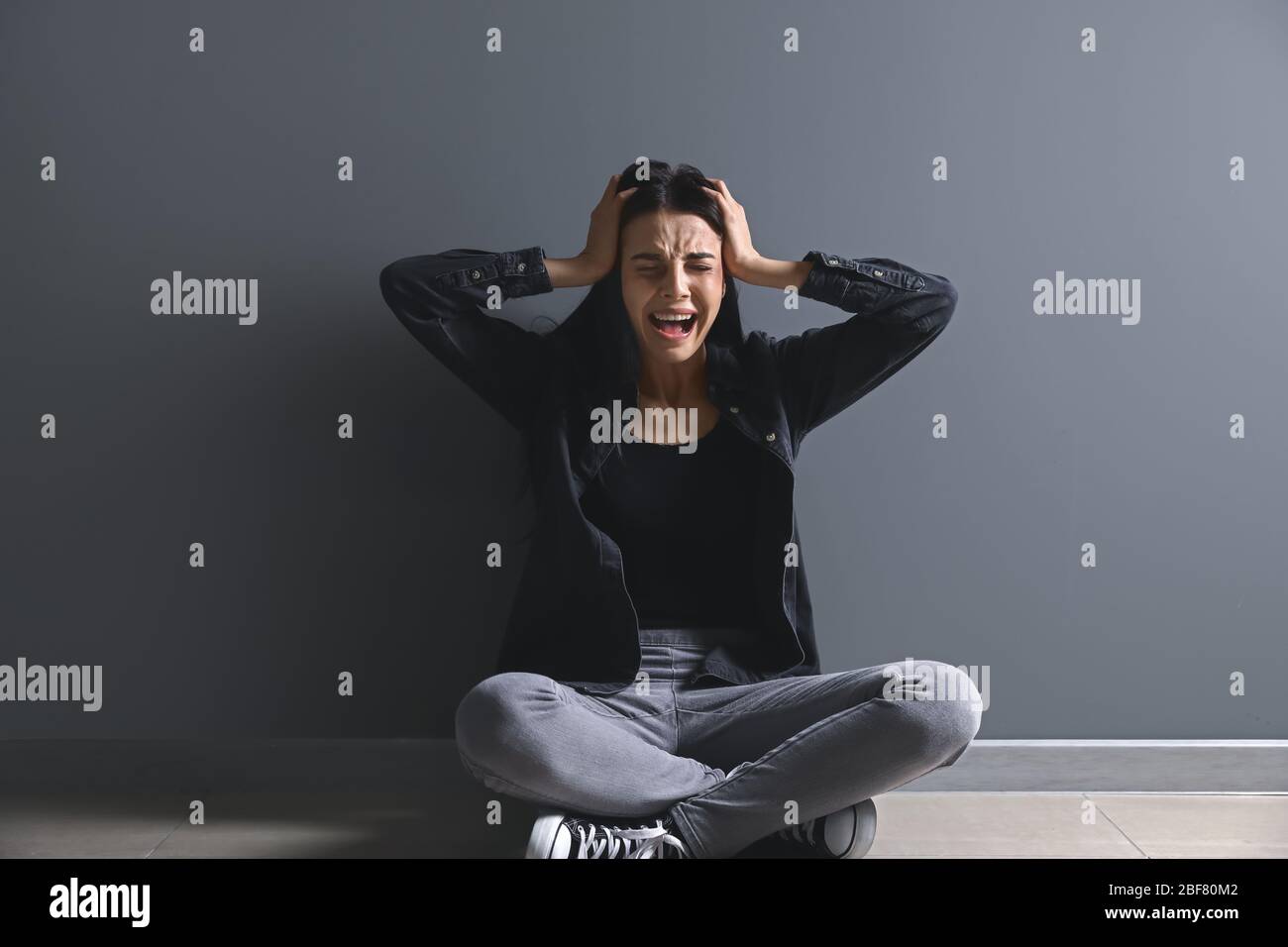 Scared female victim sitting near wall. Concept of violence Stock Photo ...