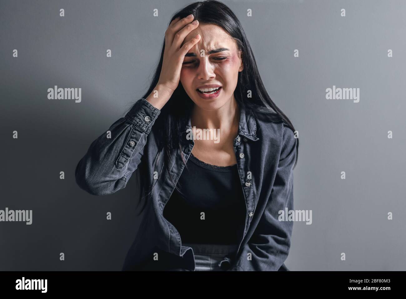 Scared female victim on grey background. Concept of violence Stock ...