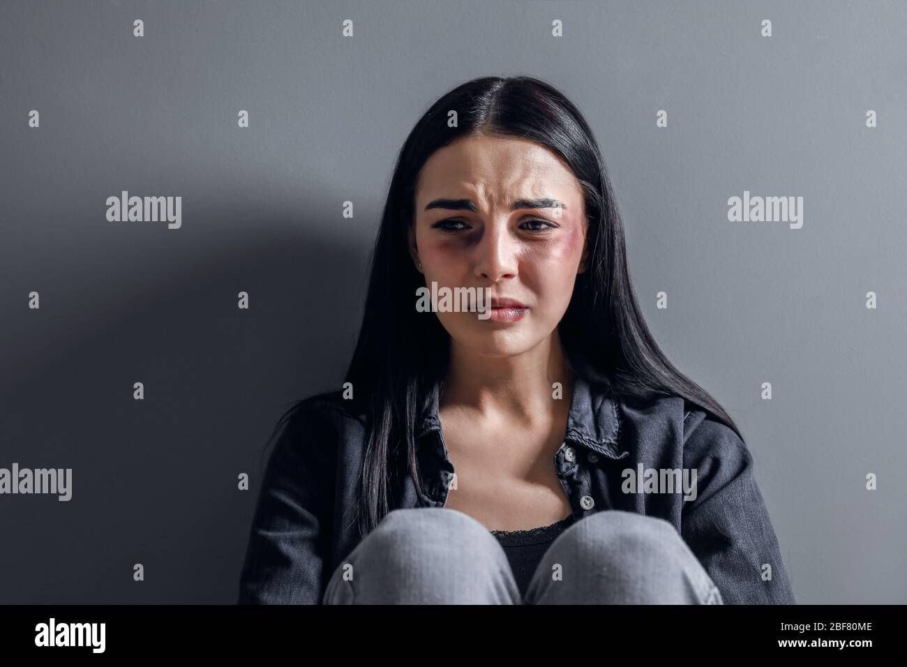 Scared female victim on grey background. Concept of violence Stock ...