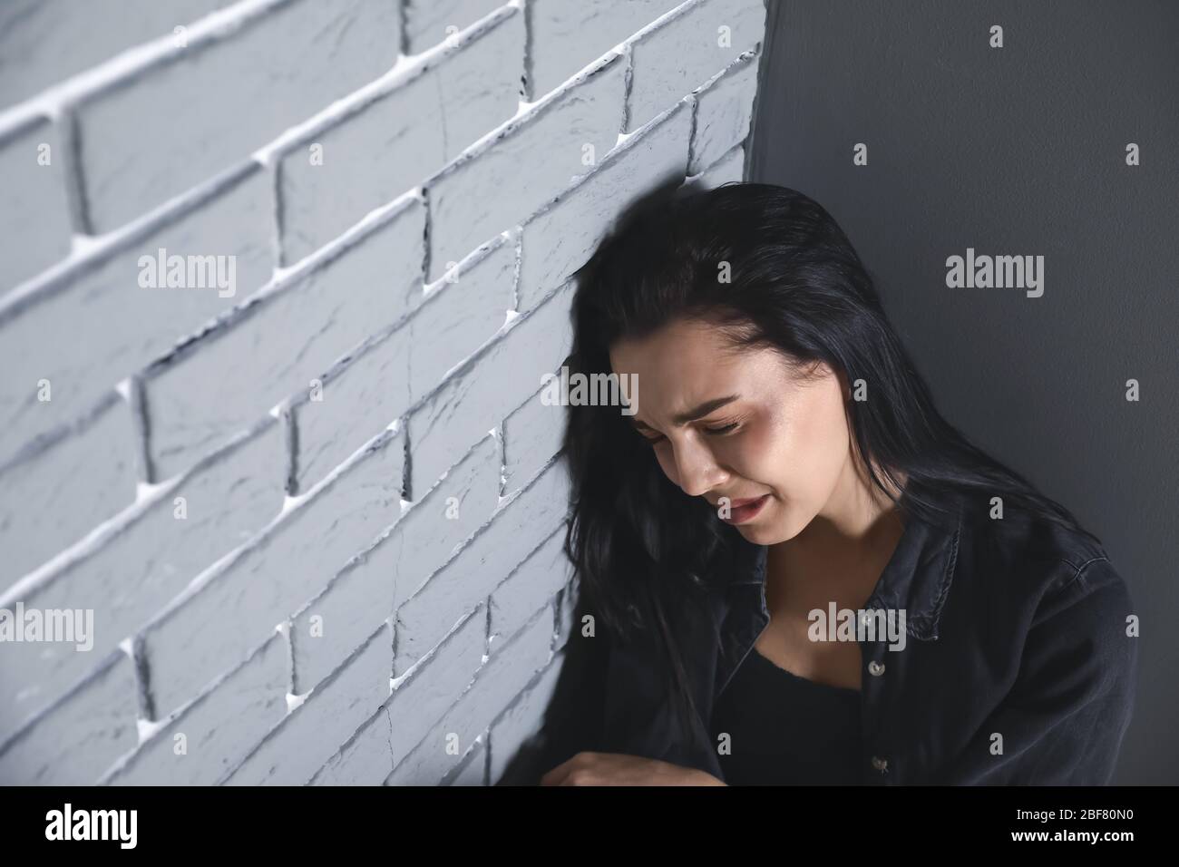 Scared female victim sitting near wall. Concept of violence Stock Photo ...