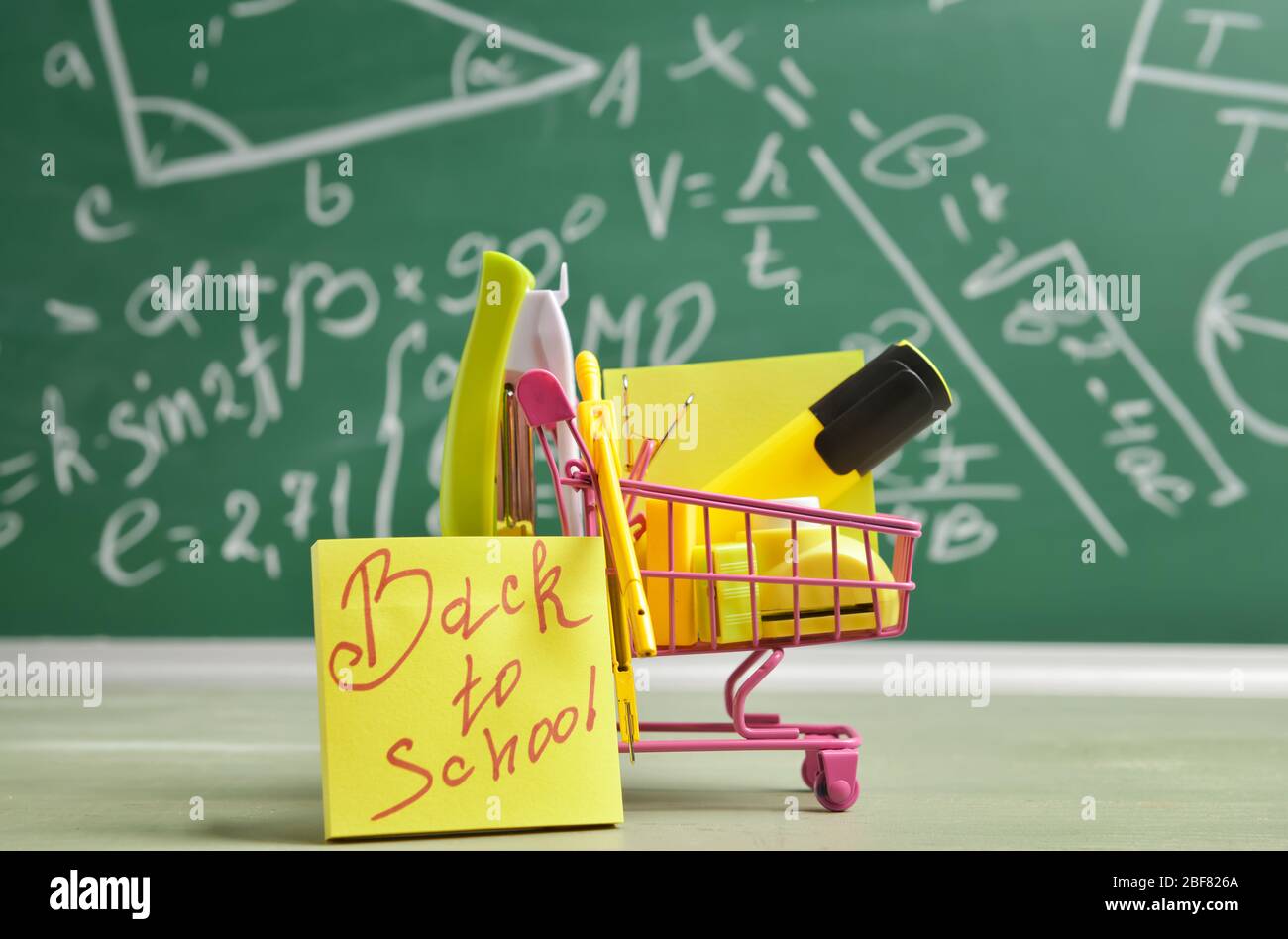 Shopping cart with school supplies on table in classroom Stock Photo ...