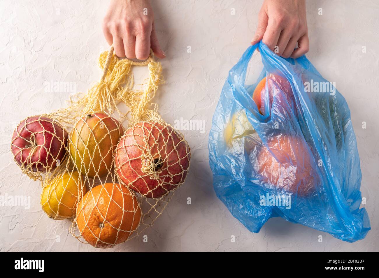 Woman hands hold mixed organic fruit, vegetables and greens in a string ...