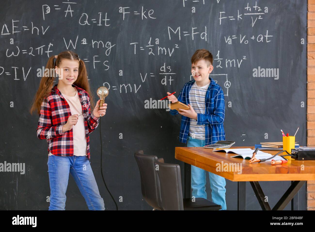 Cute little children near blackboard at physics lesson in classroom ...
