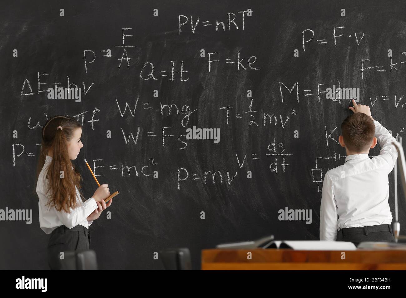 Cute little children near blackboard at physics lesson in classroom ...