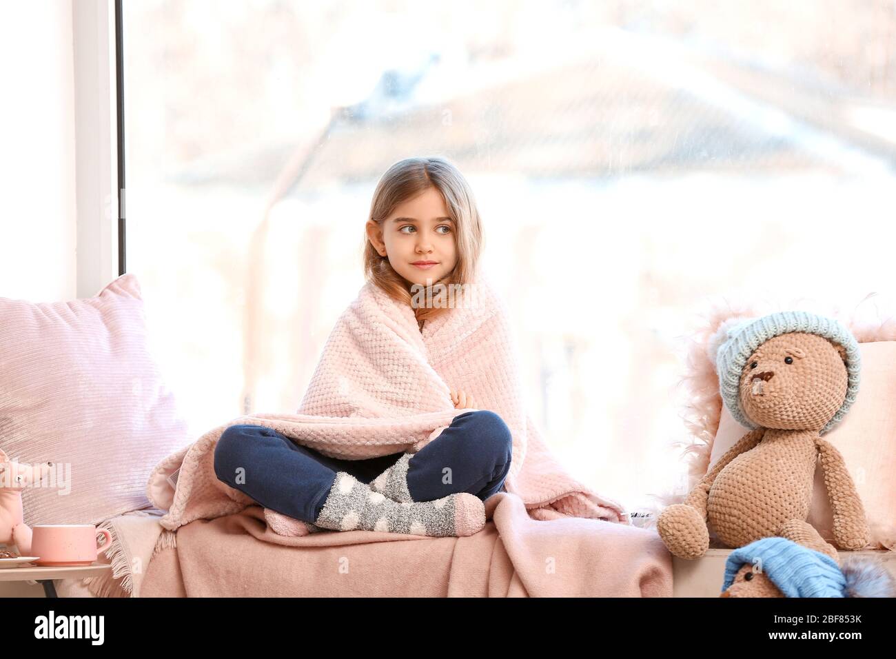 Cute little girl on window sill at home Stock Photo - Alamy