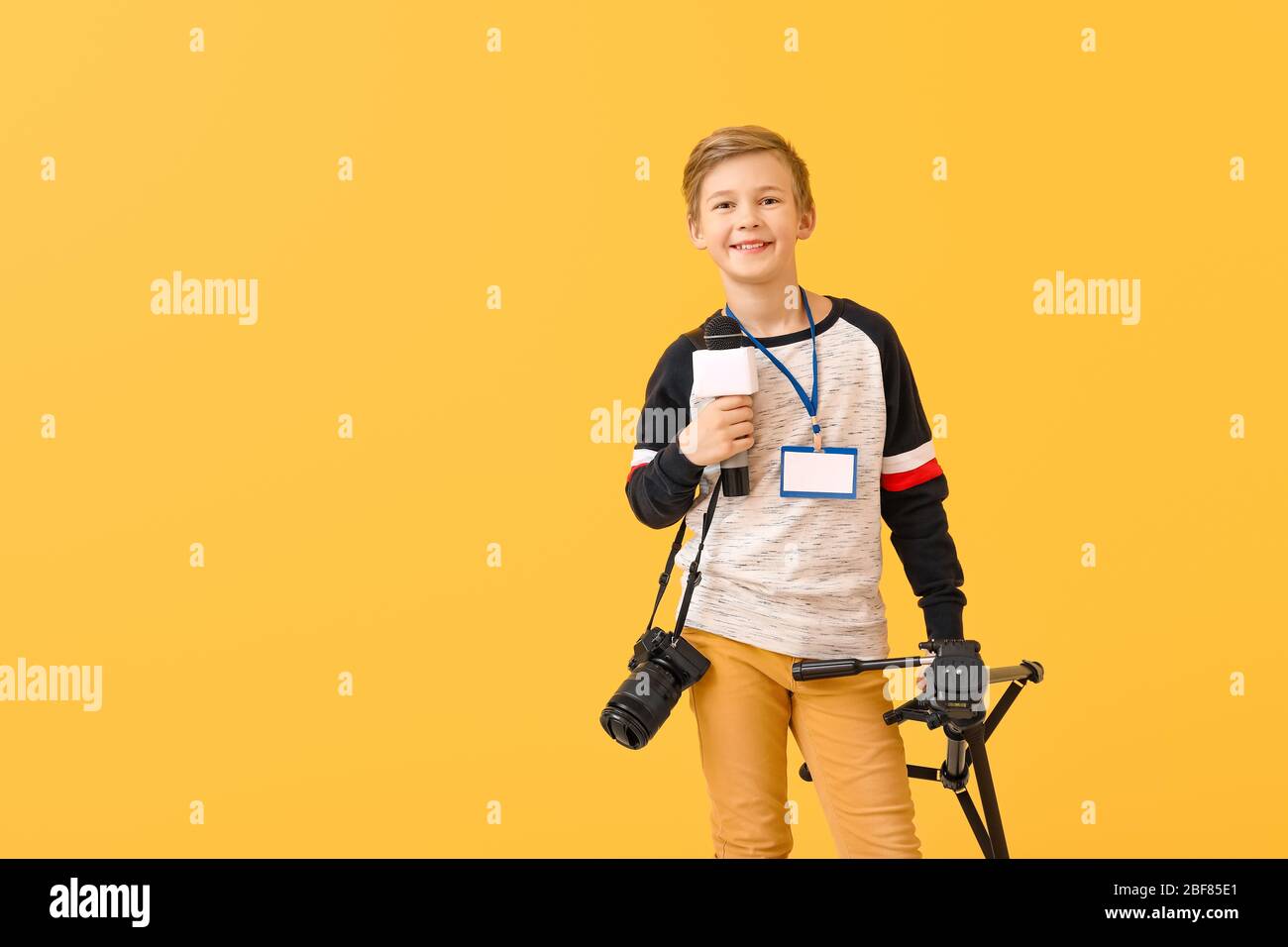 Little journalist with microphone and camera on color background Stock ...