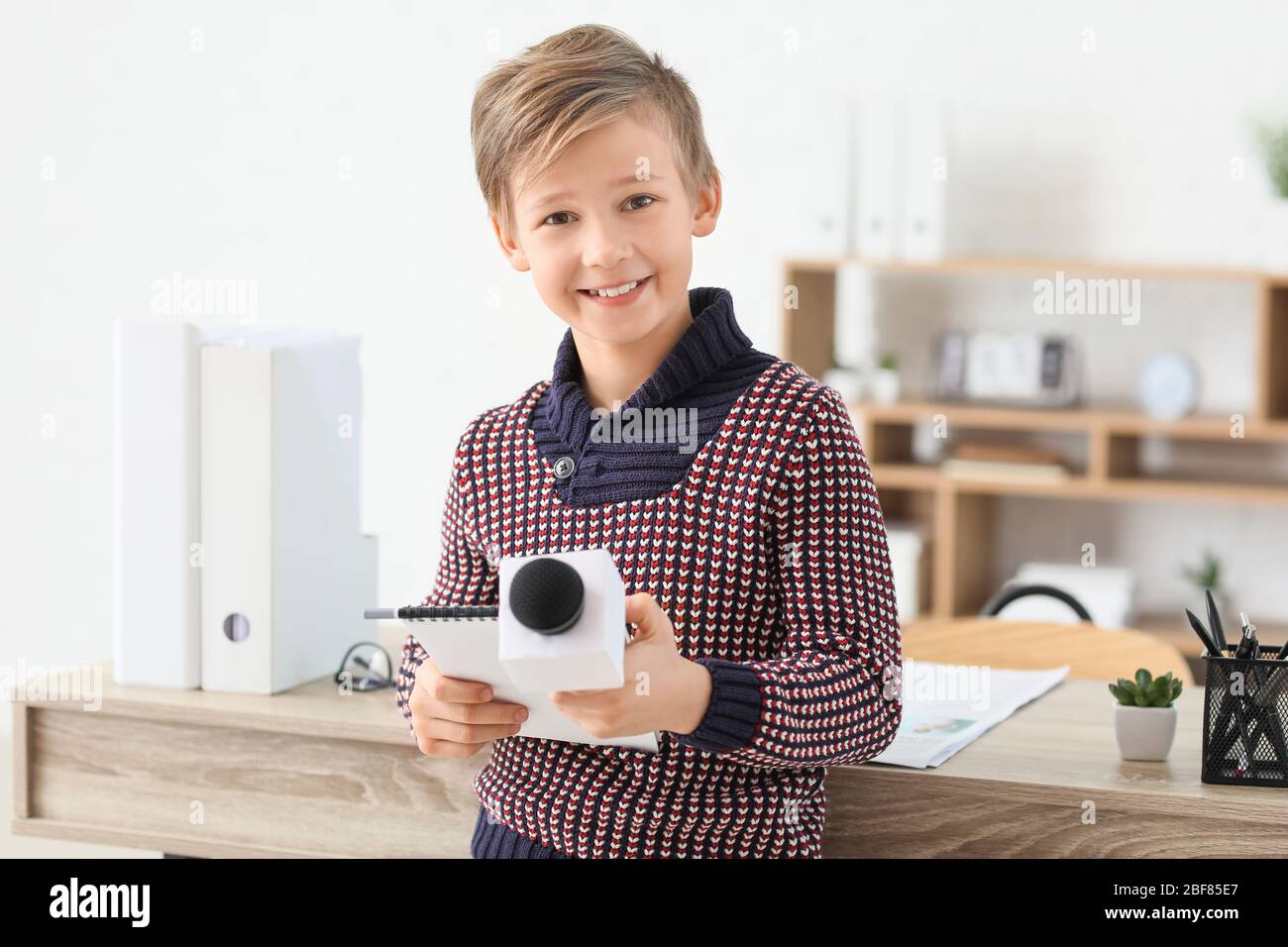 Little journalist with microphone having an interview in office Stock ...