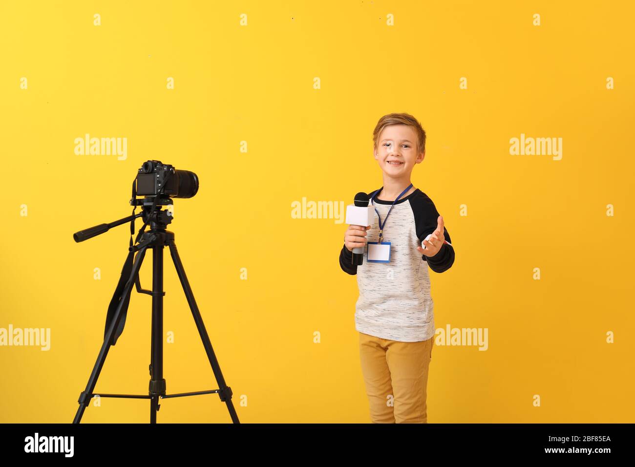 Little journalist with microphone and camera on color background Stock ...