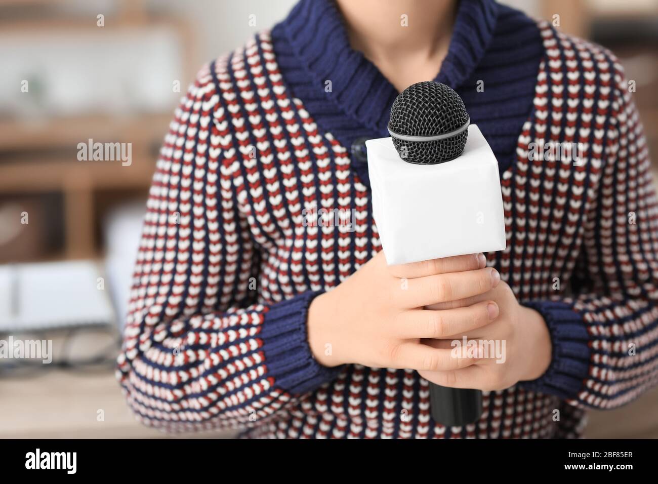 Little journalist with microphone having an interview in office ...