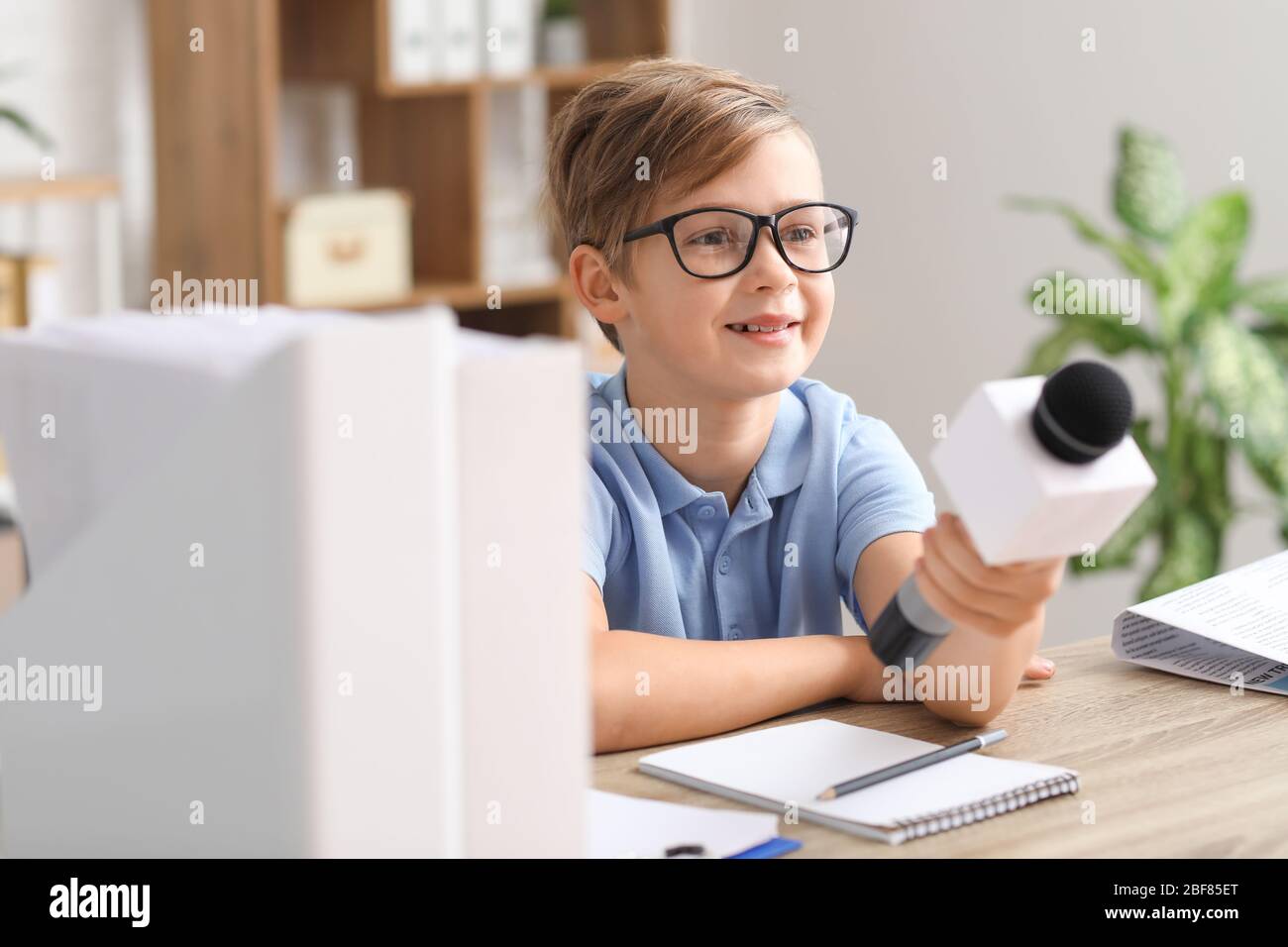 Little journalist with microphone having an interview in office Stock ...