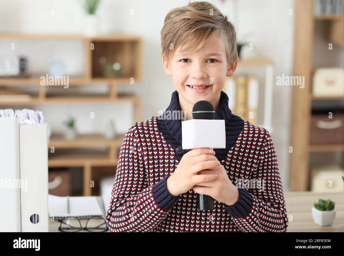 Little journalist with microphone having an interview in office Stock ...