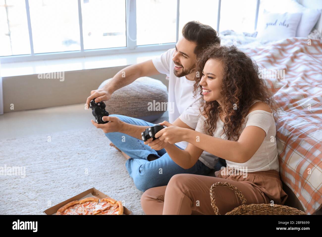 Happy young couple playing video games in bedroom Stock Photo - Alamy