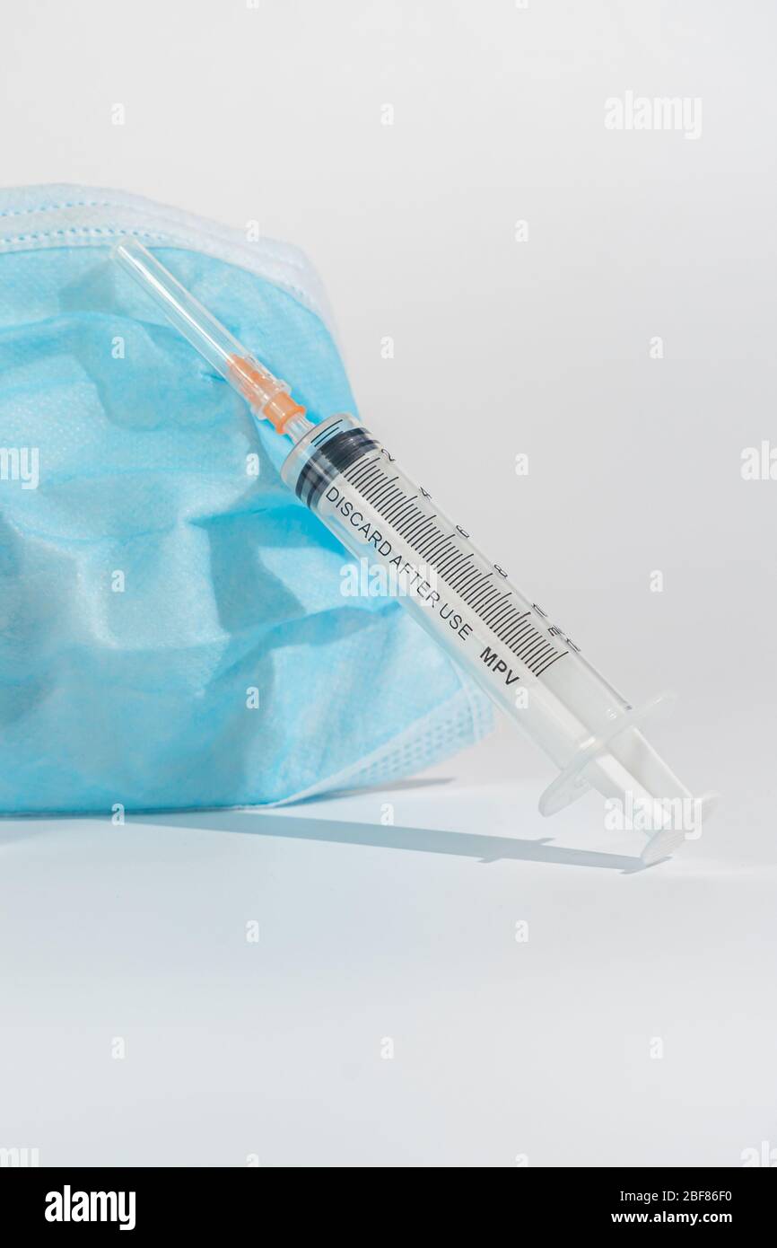 Syringe injection and surgical mask in white background Stock Photo - Alamy