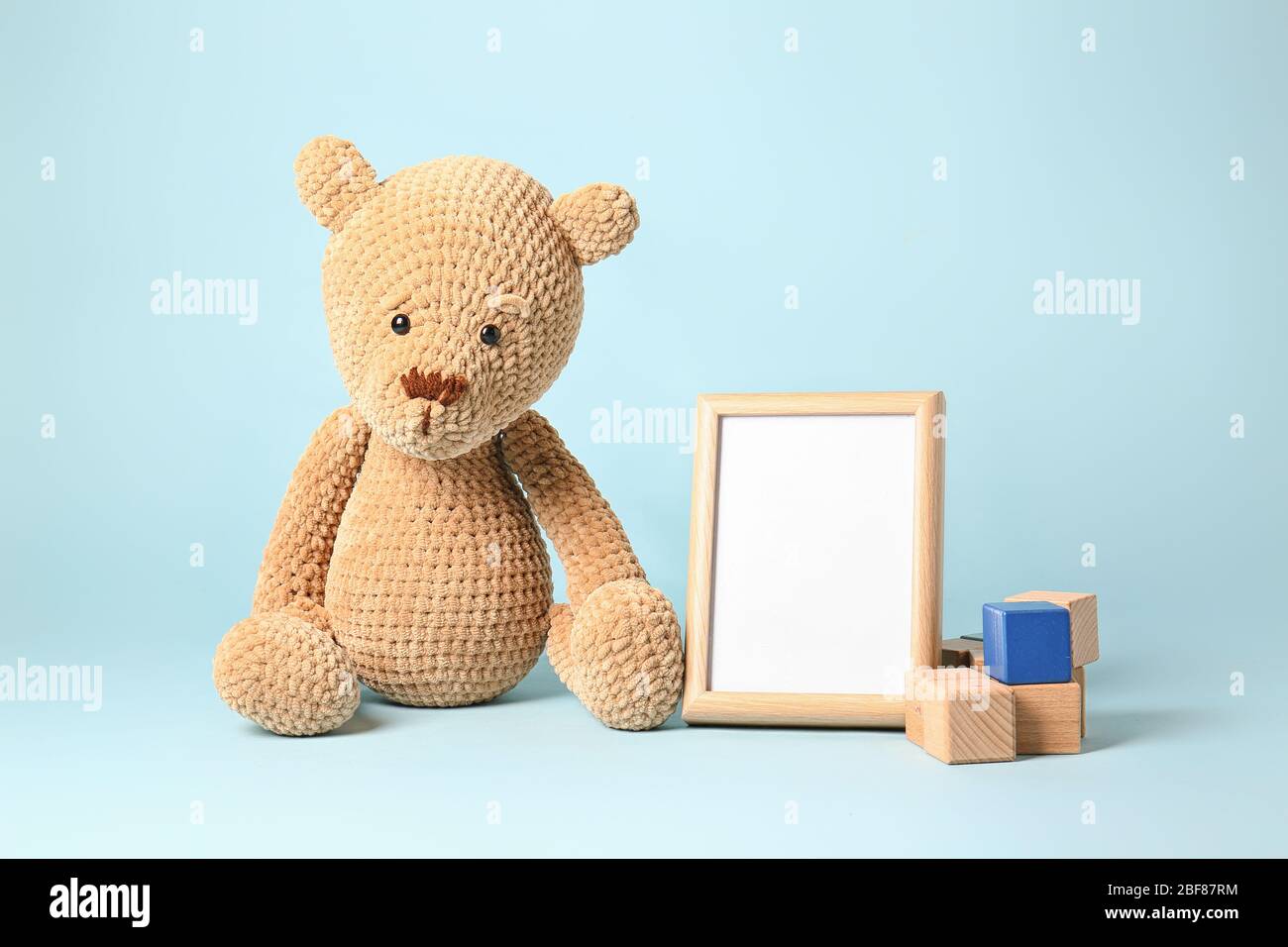 Teddy bear with photo frame and cubes on color background Stock Photo ...