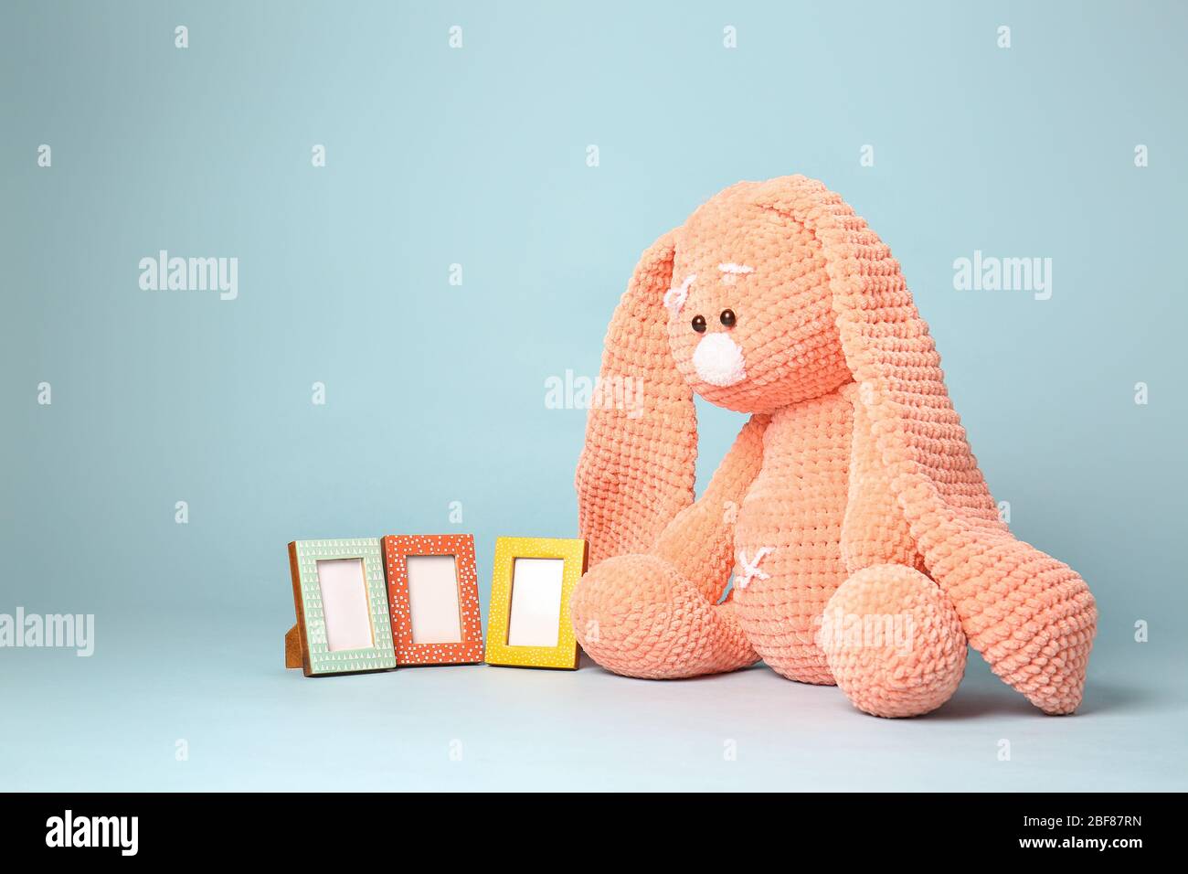 Cuddly bunny with photo frames on color background Stock Photo - Alamy