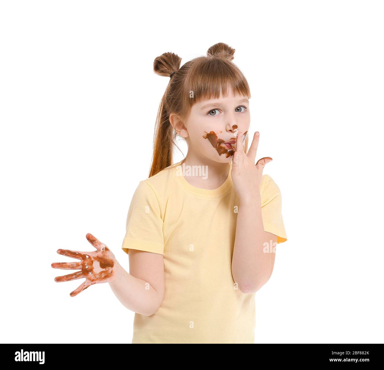 Cute little girl with chocolate on hands and face against white ...