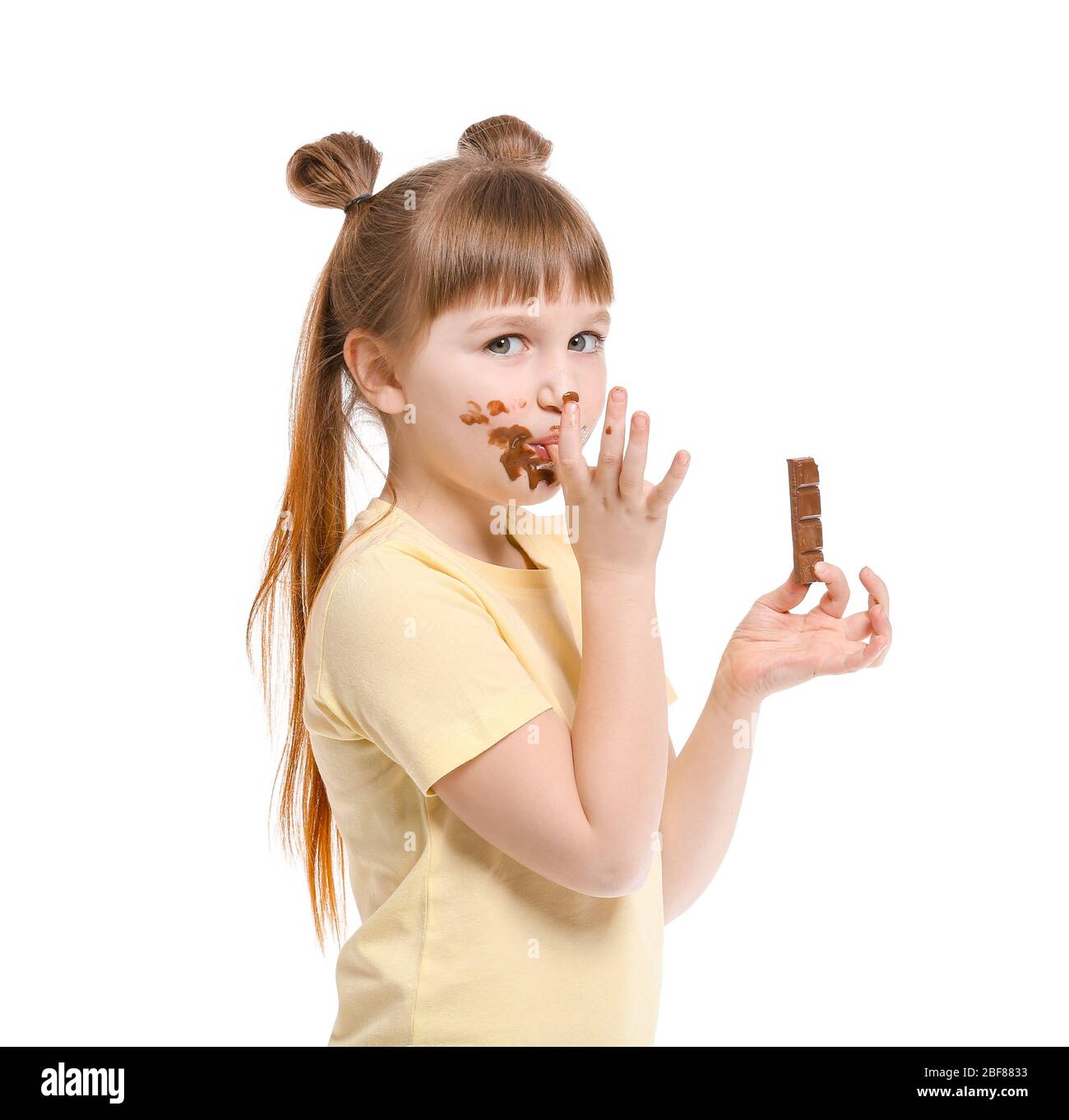 Cute little girl eating chocolate on white background Stock Photo - Alamy