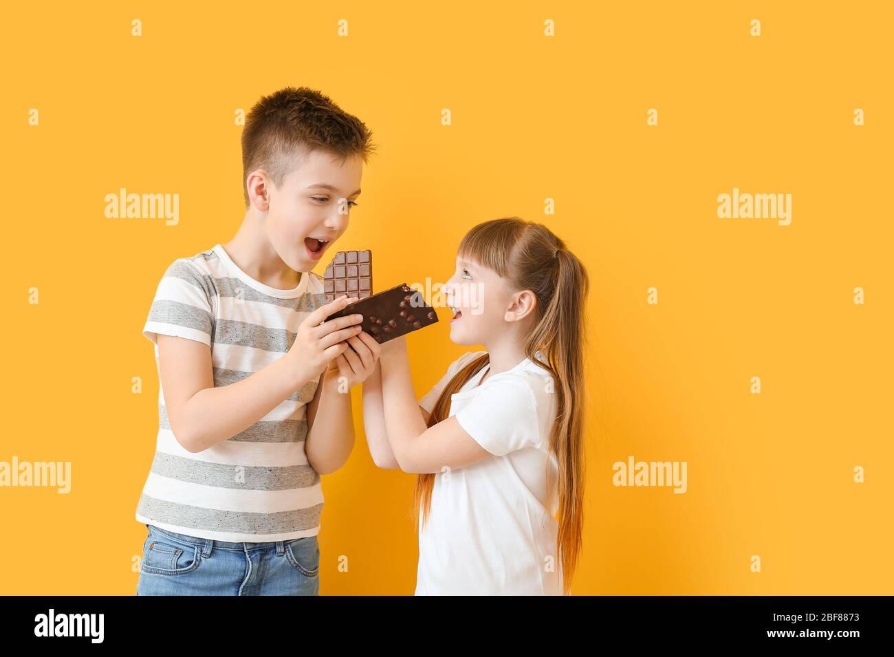 Cute little children eating chocolate on color background Stock Photo ...