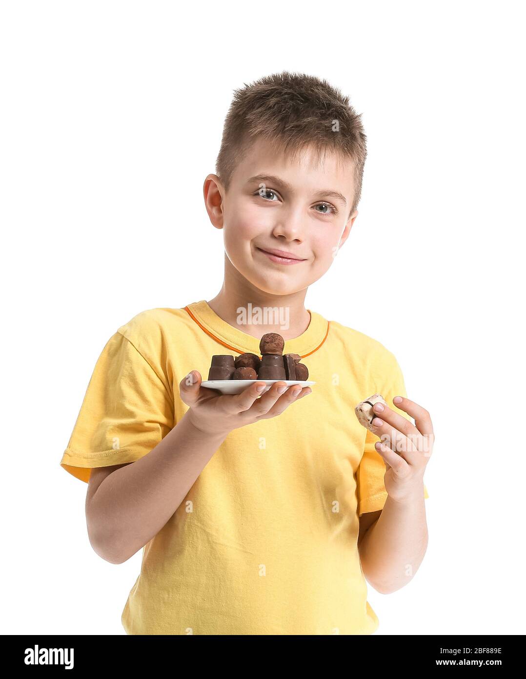 Cute little boy with chocolate candies on white background Stock Photo ...