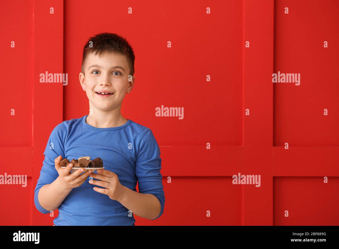Cute little boy with chocolate candies on color background Stock Photo ...