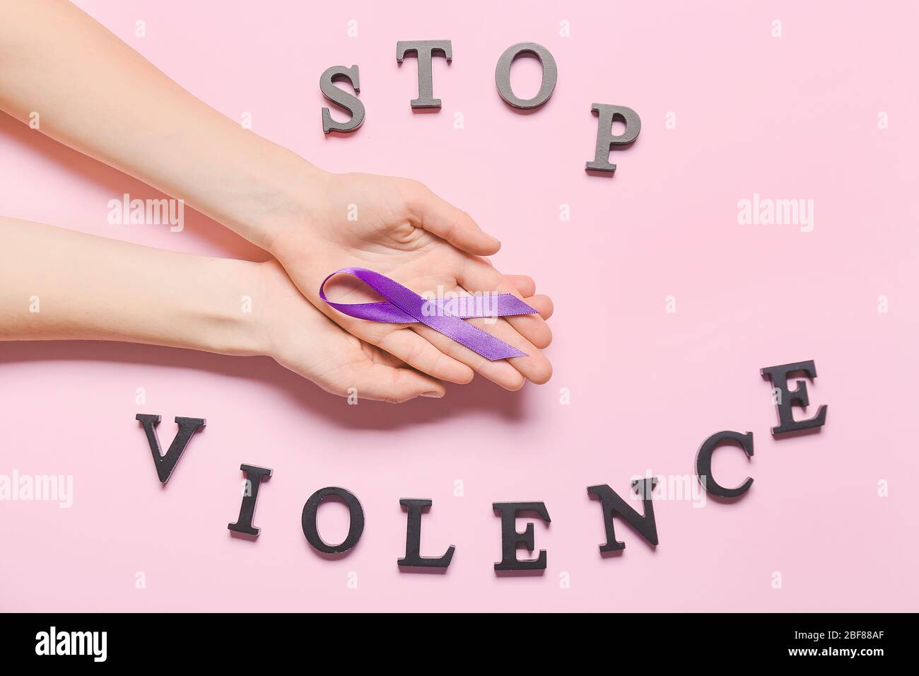 Female hands with violet ribbon and text STOP VIOLENCE on color ...