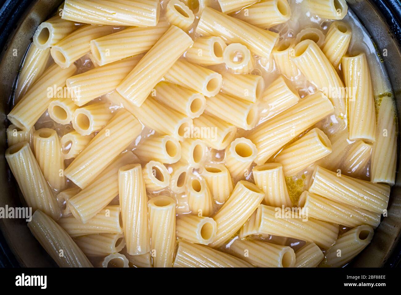 Yellow italian cooked pasta tortiglioni in a pan. Traditional food ...