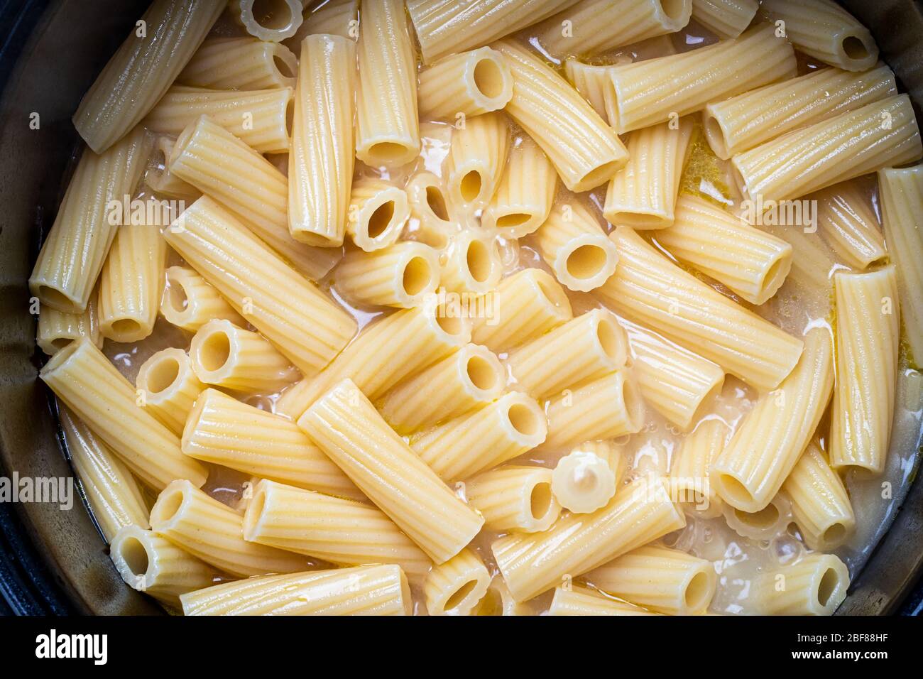 Yellow italian cooked pasta tortiglioni in a pan. Traditional food ...