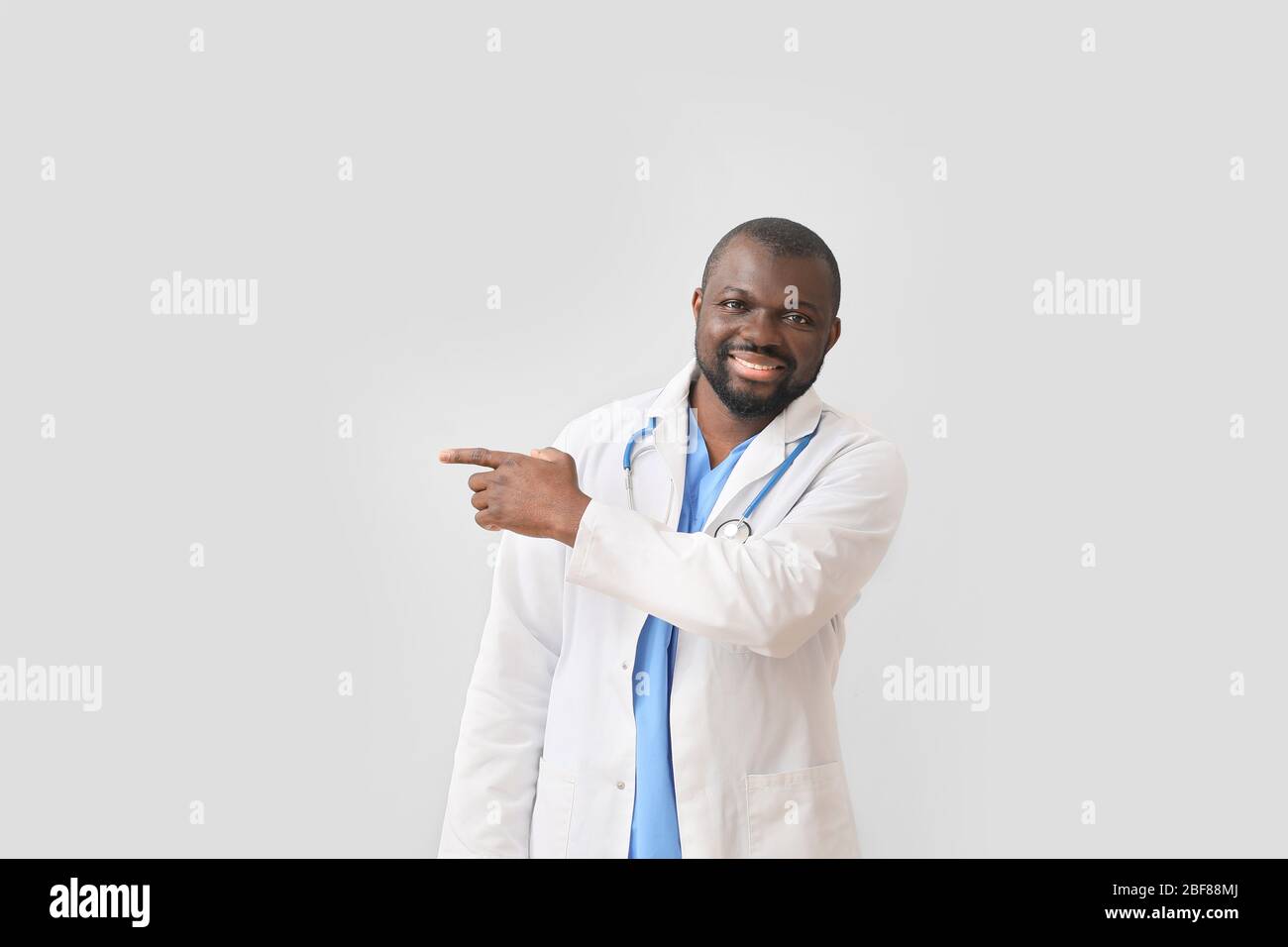 African-American doctor pointing at something on light background Stock ...