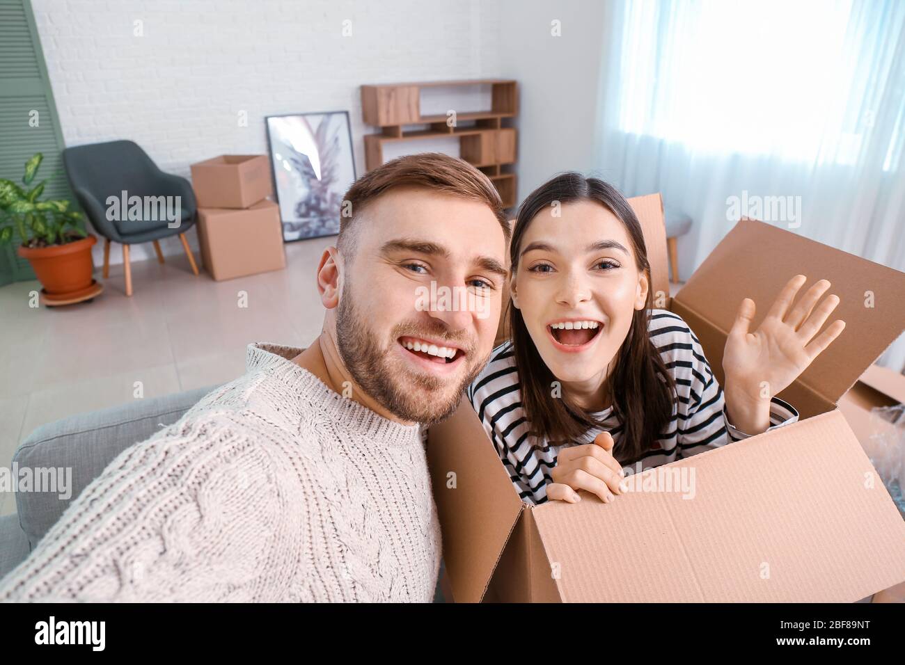 Young couple having fun while unpacking things in their new flat on ...