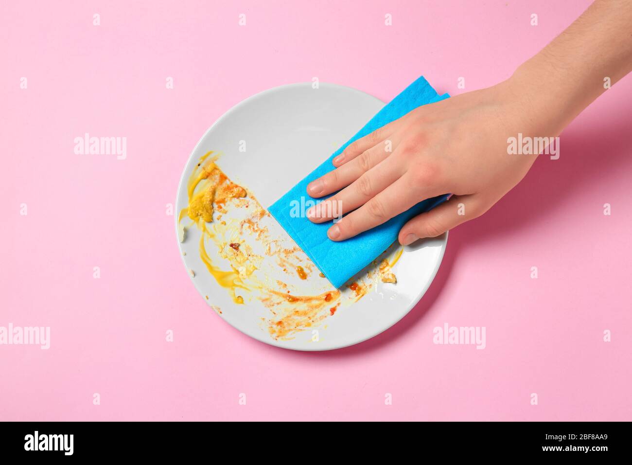 Woman cleaning plate on color background Stock Photo - Alamy