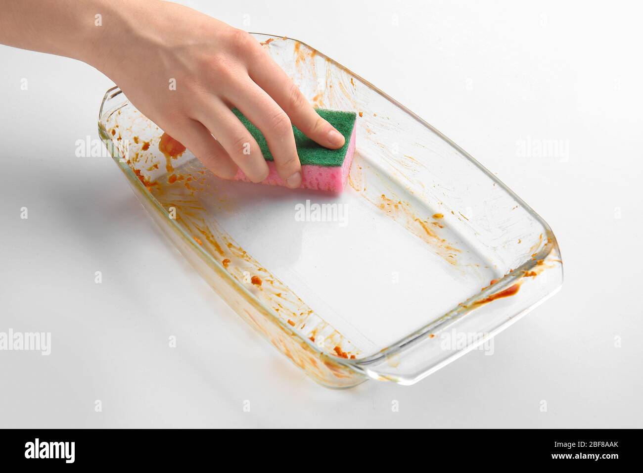 Woman cleaning baking dish on white background Stock Photo - Alamy