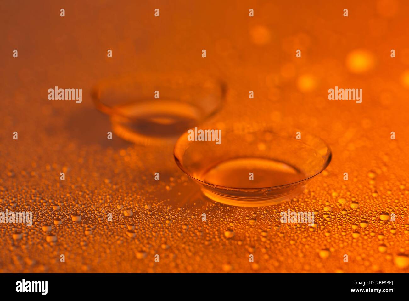 Contact lenses and water drops on color background Stock Photo - Alamy