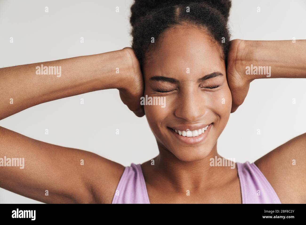 Portrait of african american funny woman laughing and covering her ears ...