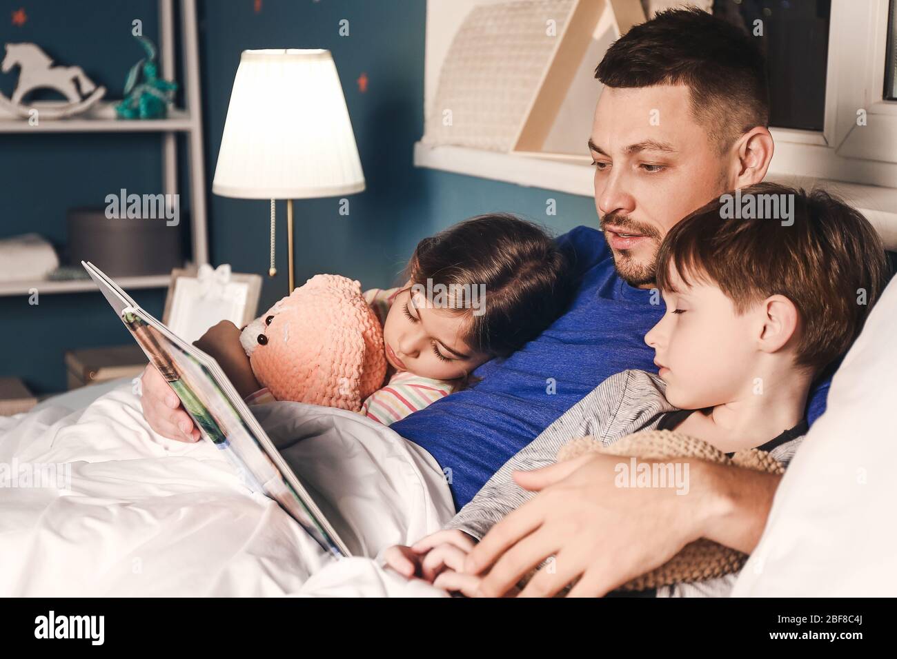 Father reading bedtime story to his little children at home Stock Photo ...