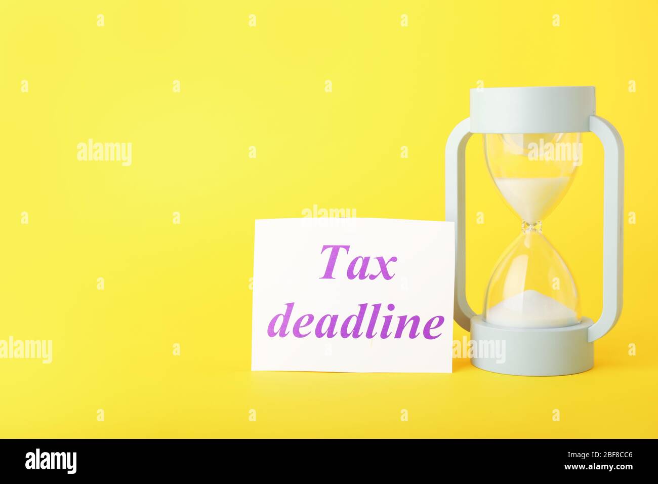 Hourglass and paper with text TAX TIME on color background Stock Photo ...