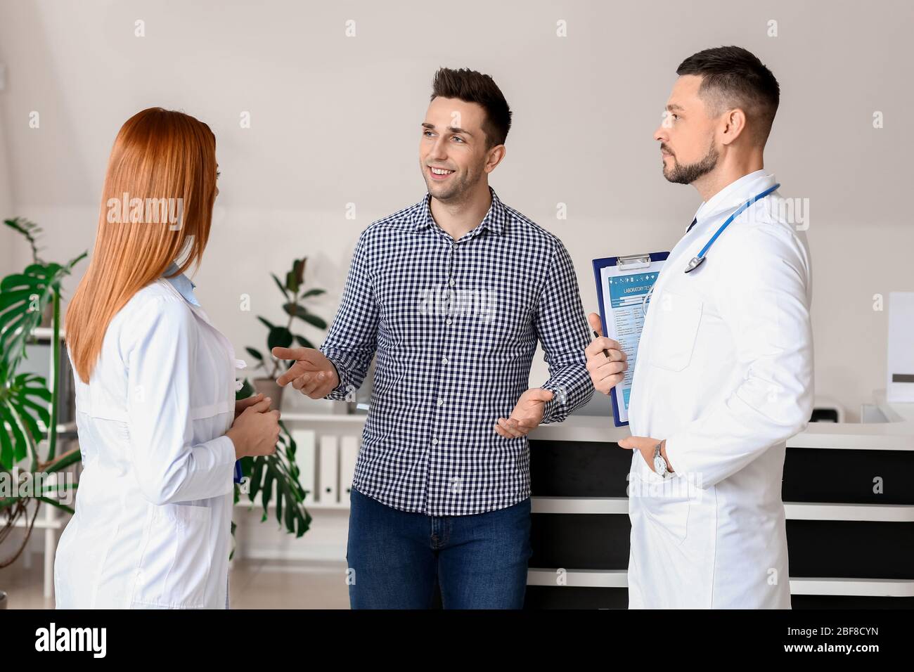 Doctors with patient in hall of clinic Stock Photo - Alamy