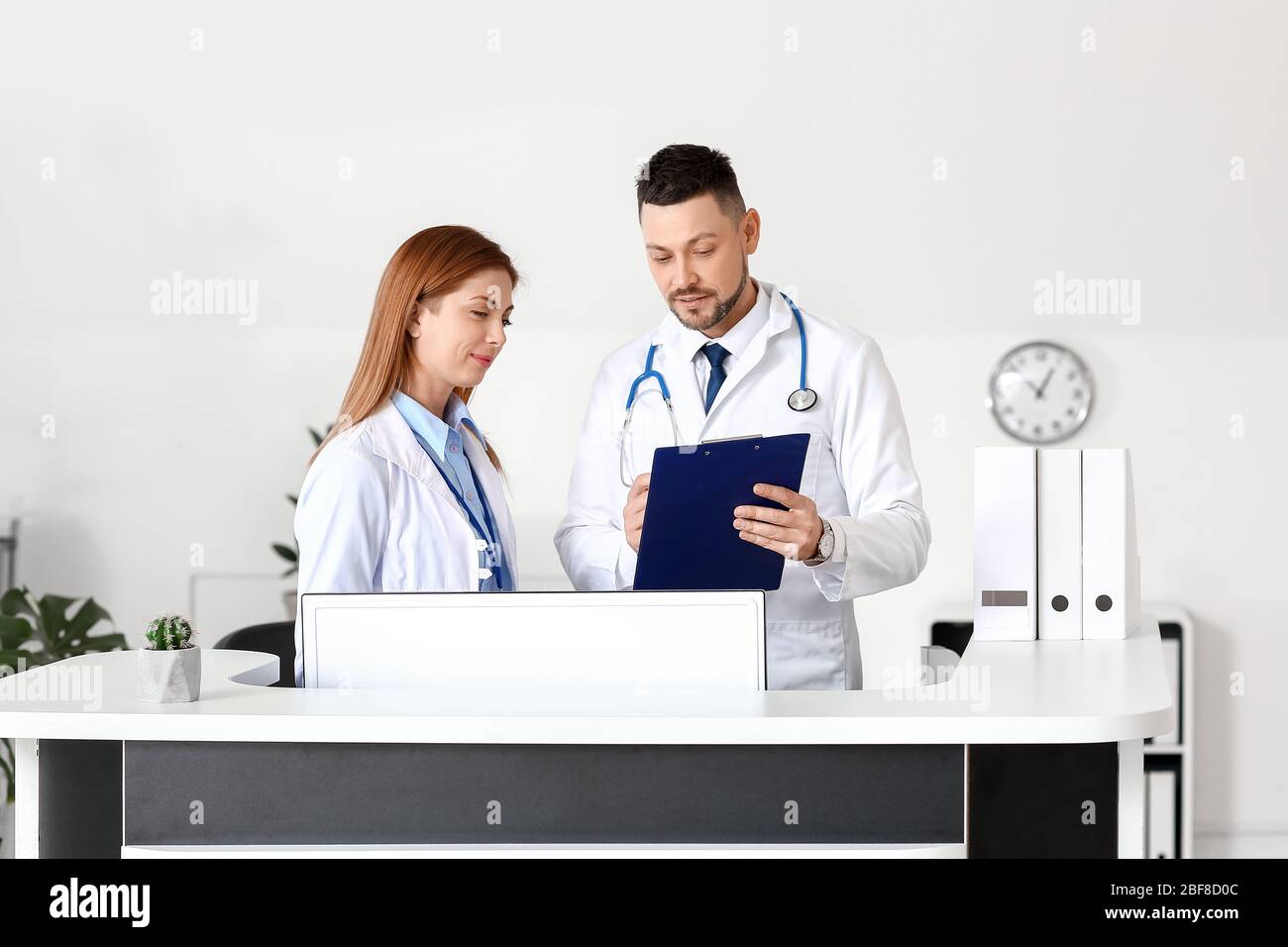 Female medical assistant with doctor working in clinic Stock Photo - Alamy