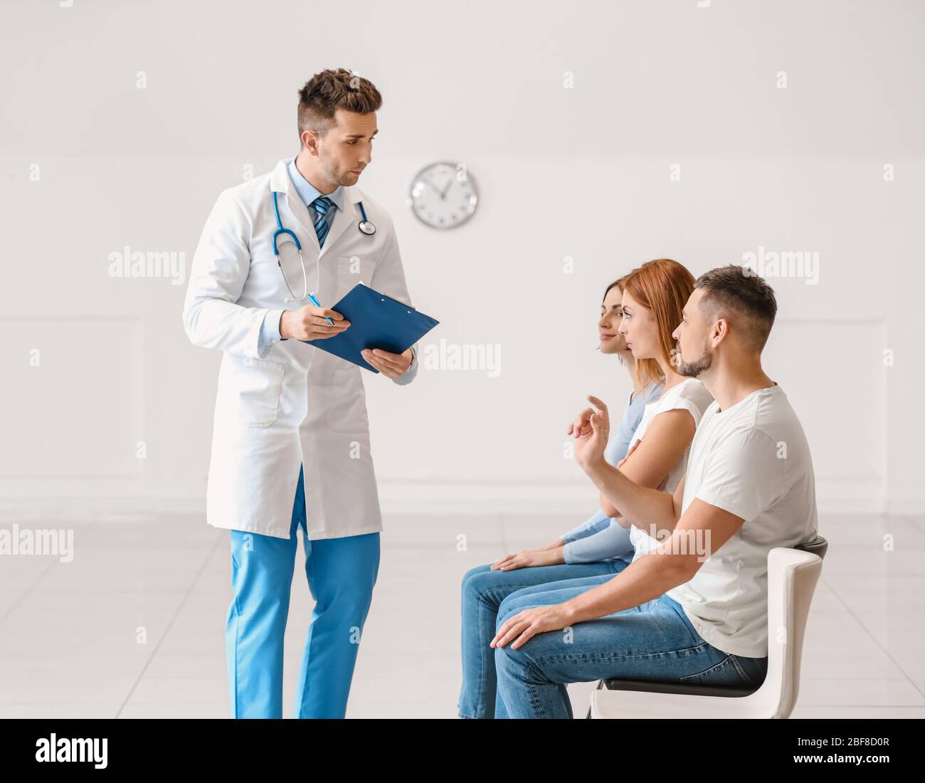 Male doctor with patients in hall of clinic Stock Photo - Alamy