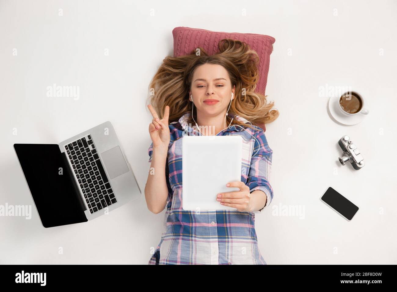 Young caucasian woman using devices, gadgets isolated on white studio background. Concept of ...