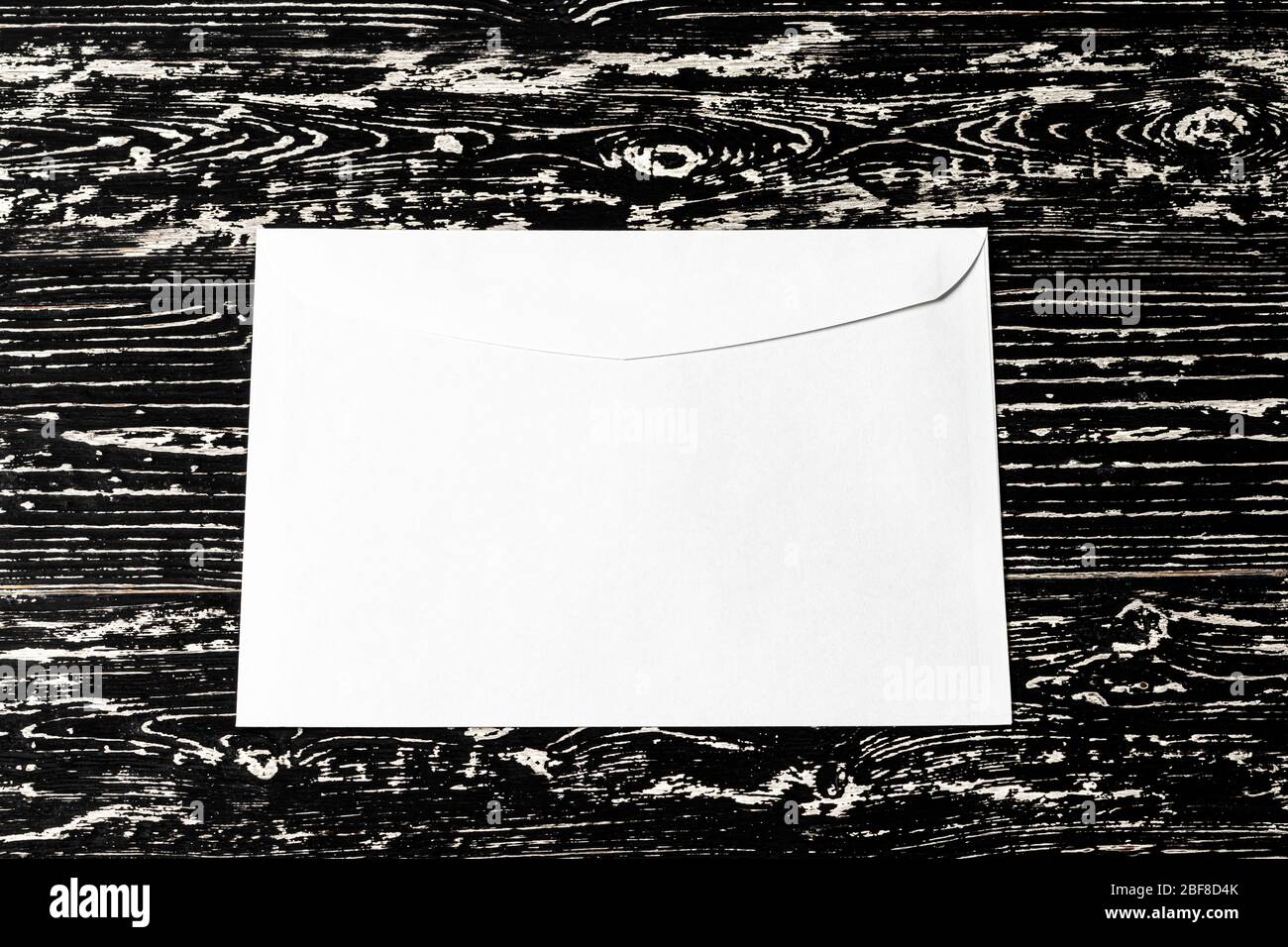 White postal envelope on a black wooden table. Abstract background for ...