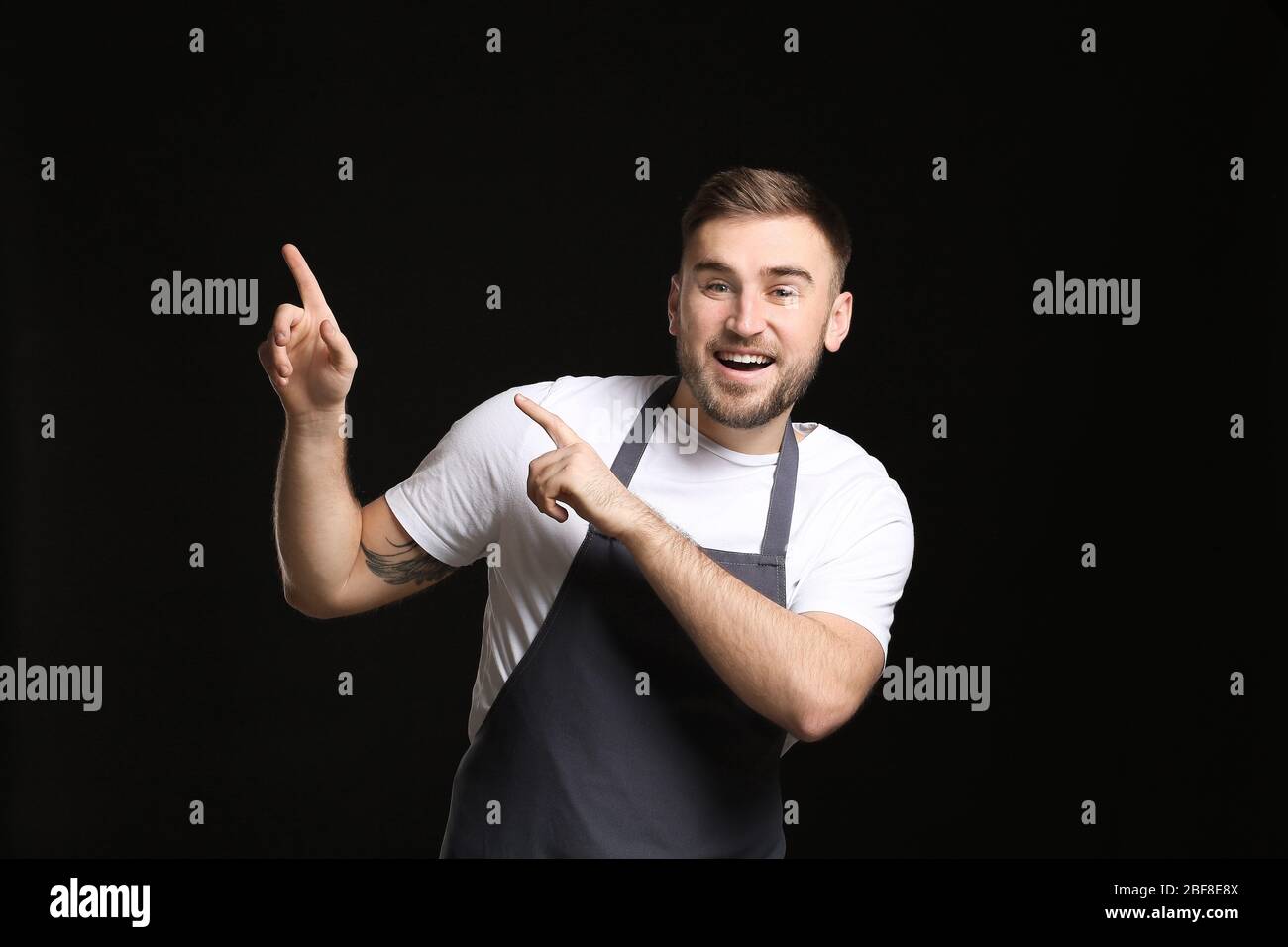 Handsome male chef pointing at something on dark background Stock Photo ...