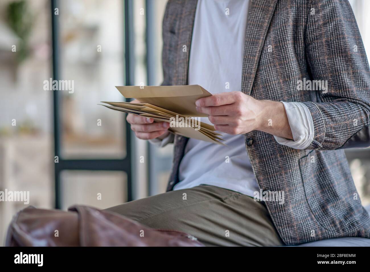 Stylish man sitting and opening the envelope Stock Photo - Alamy