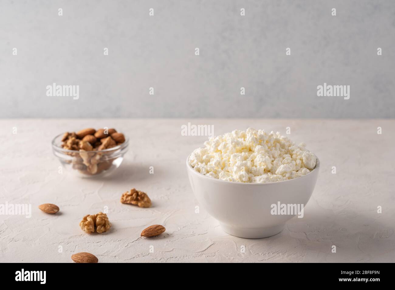 Cottage cheese in a bowl and almonds on a light background Stock Photo ...
