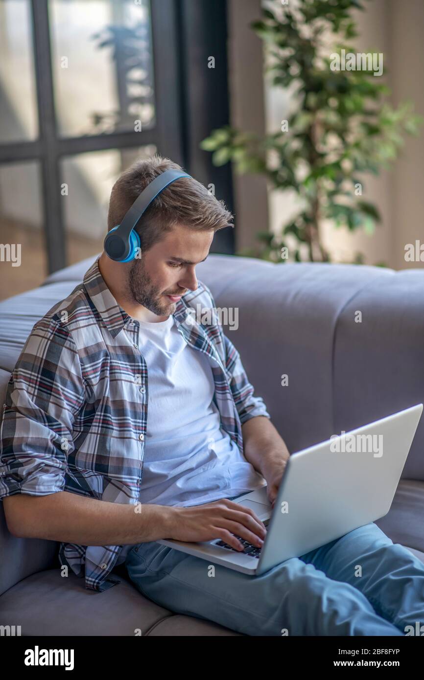 Young man in a checkered shirt writing an email Stock Photo - Alamy